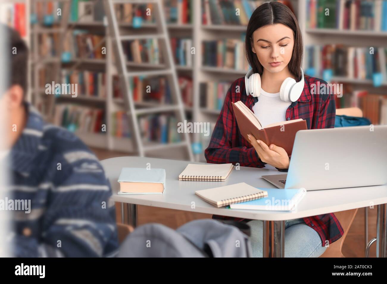 Female student reading book while preparing for exam in library Stock ...