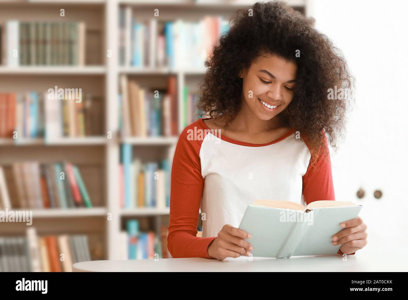 African-American student reading book while preparing for exam in ...