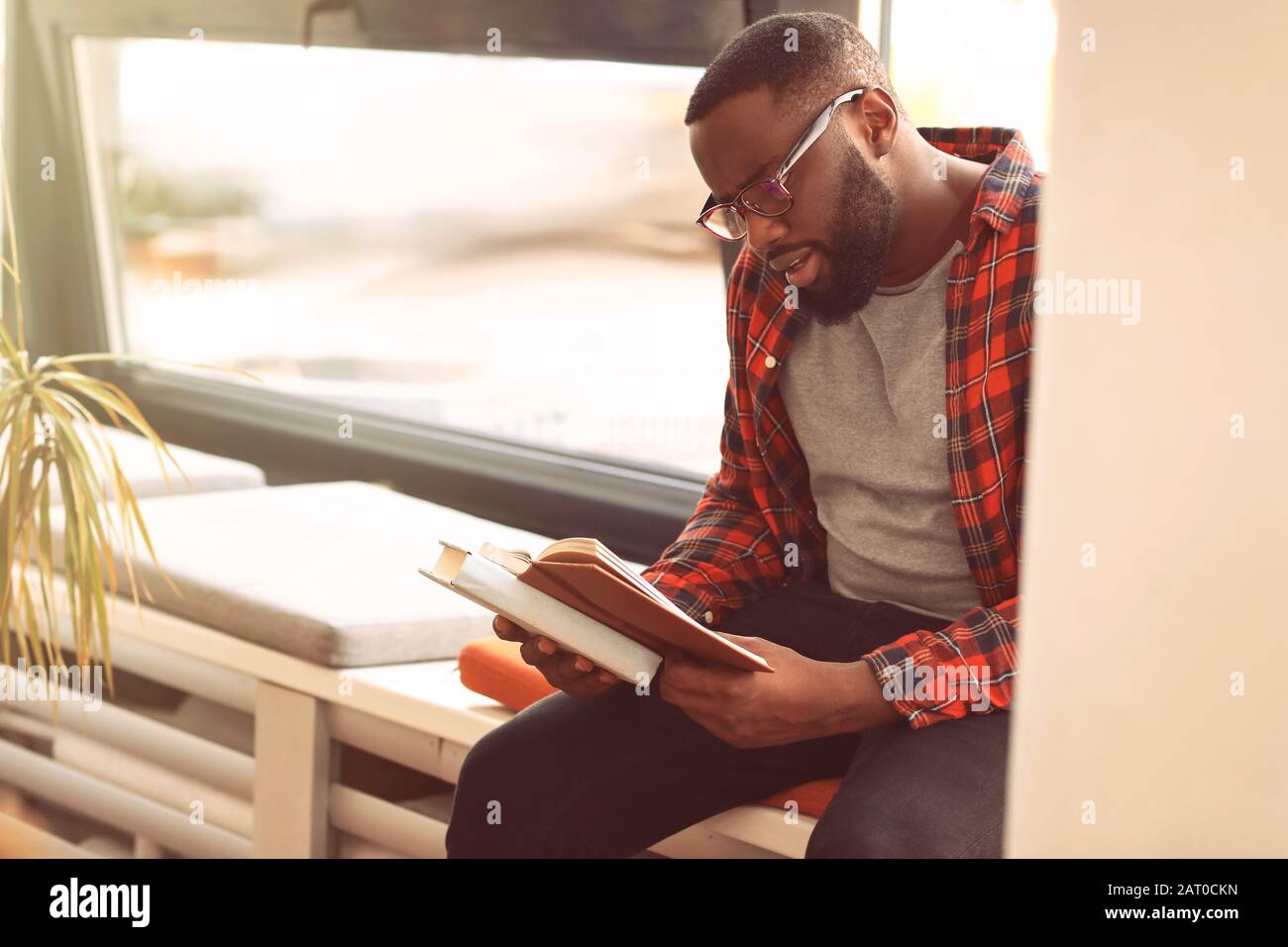 African-American student reading book while preparing for exam in ...