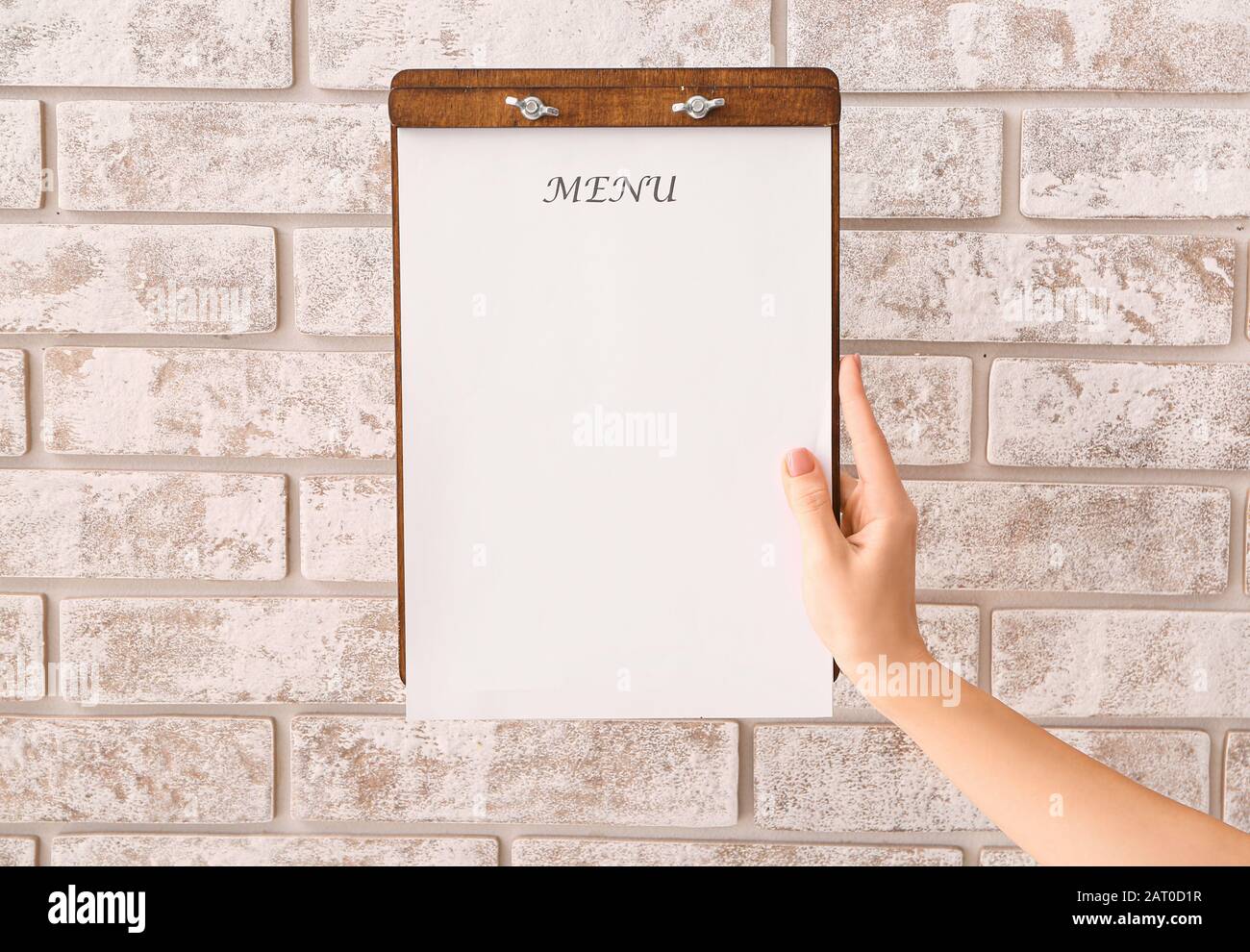 Female hand with blank menu on brick background Stock Photo - Alamy