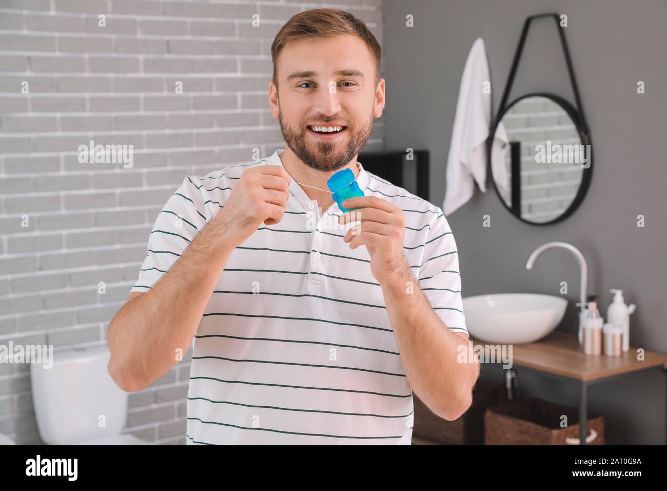 Handsome man flossing teeth in bathroom Stock Photo - Alamy