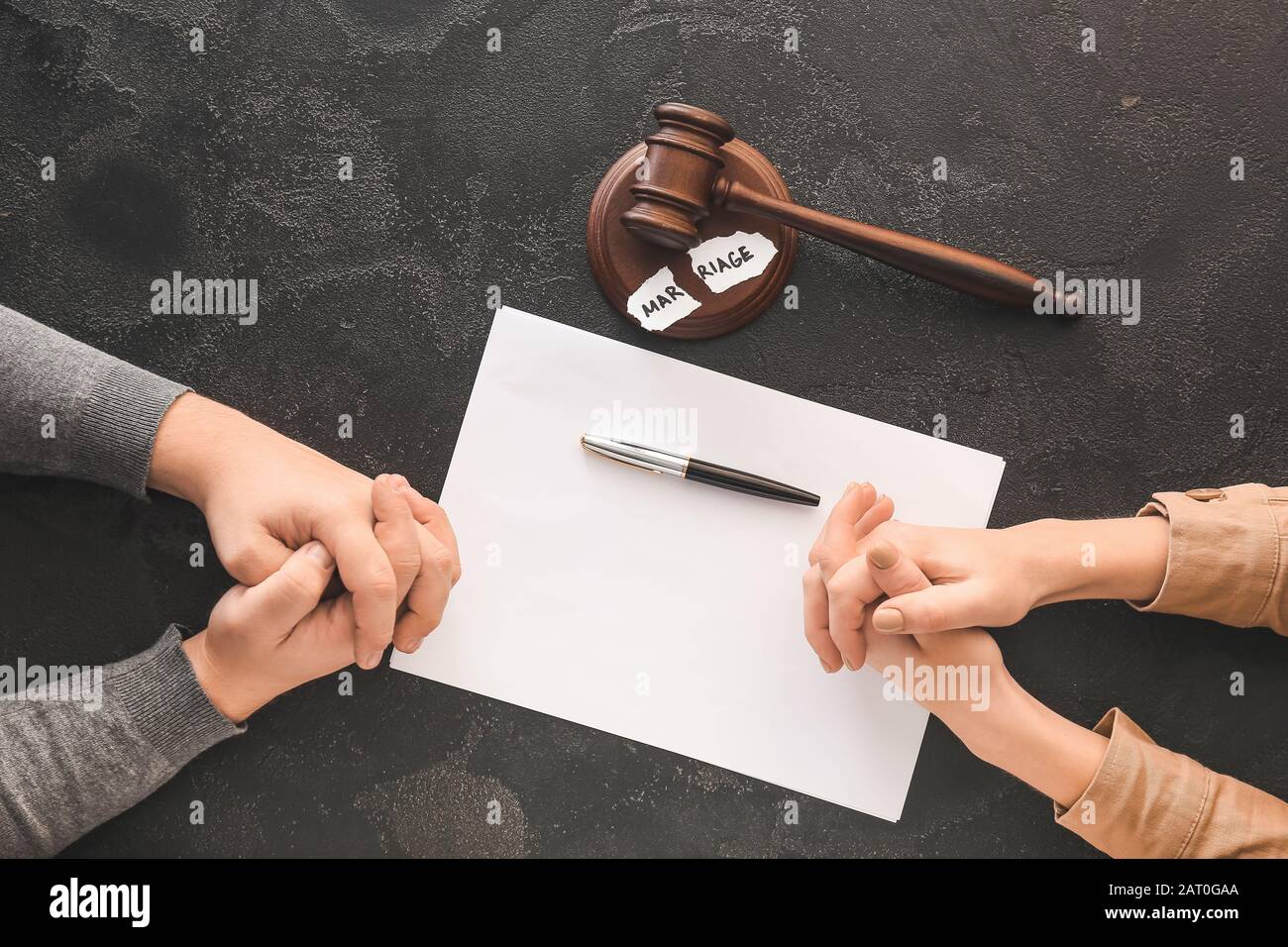 Hands of couple with sheet of paper and judge's gavel on dark ...