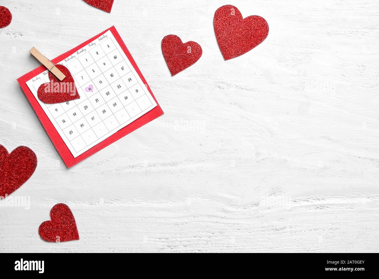 Calendar with marked date of Valentine's Day and red hearts on white ...