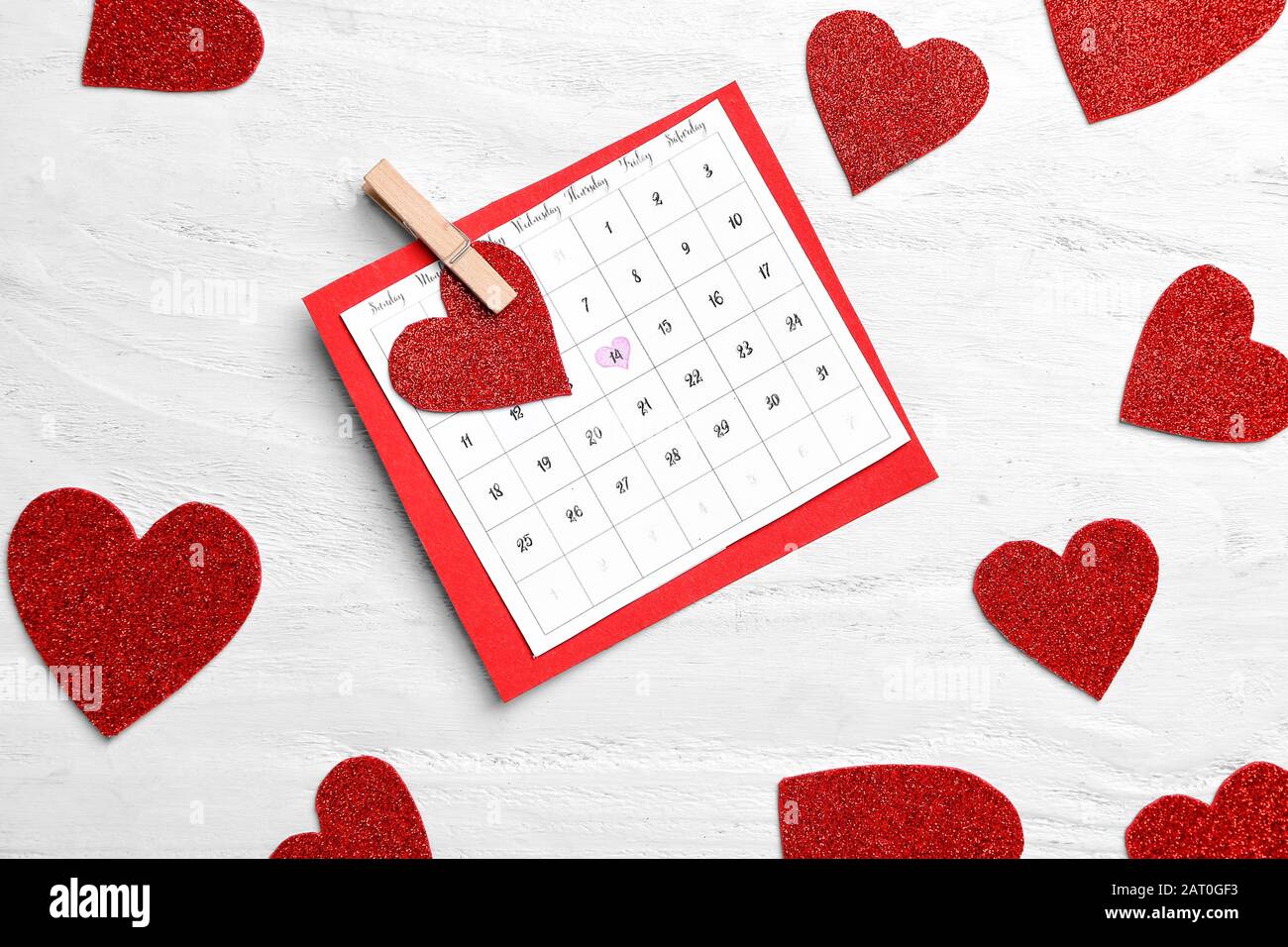 Calendar with marked date of Valentine's Day and red hearts on white ...