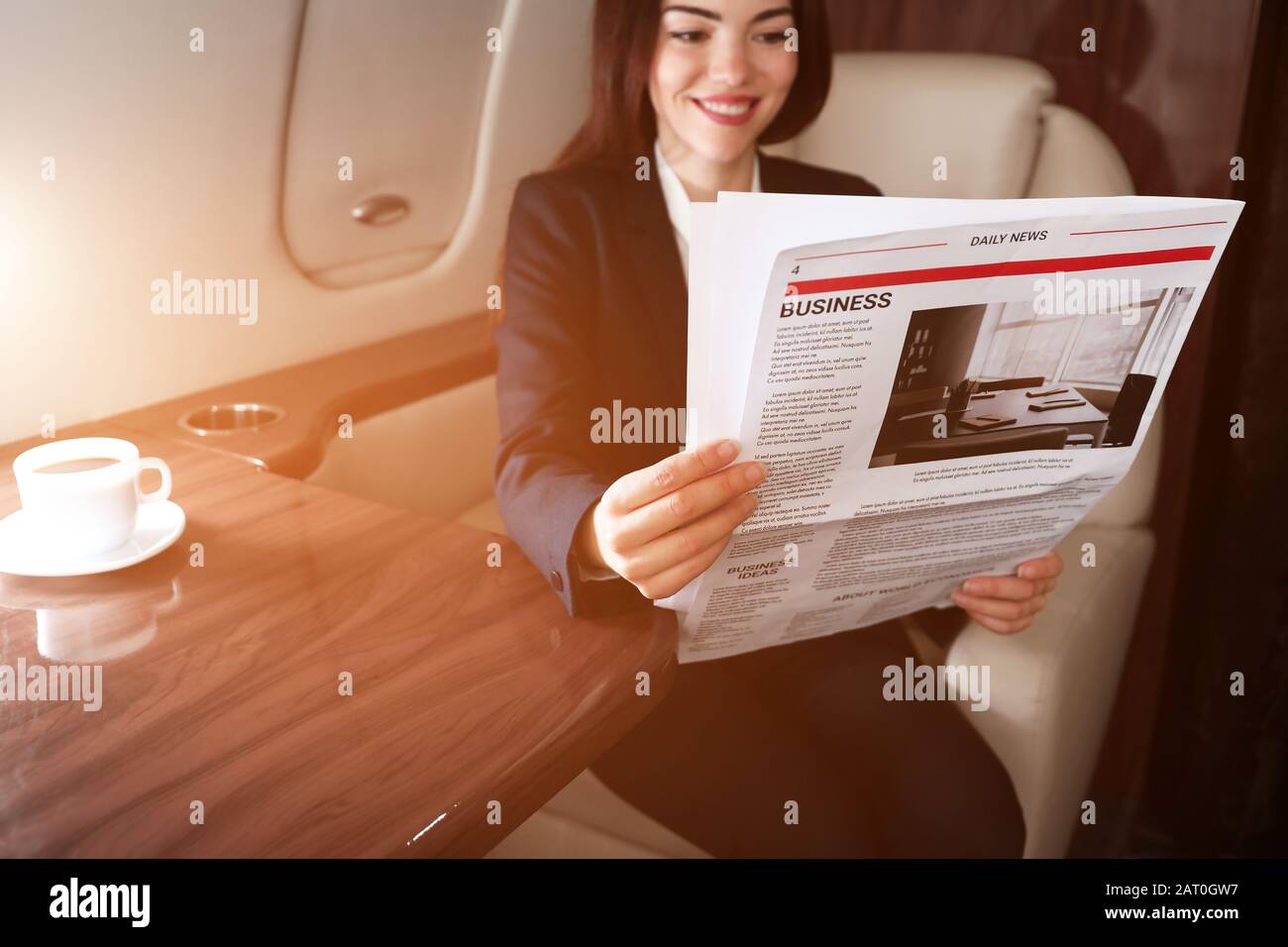 Businesswoman reading newspaper on board the modern private airplane ...