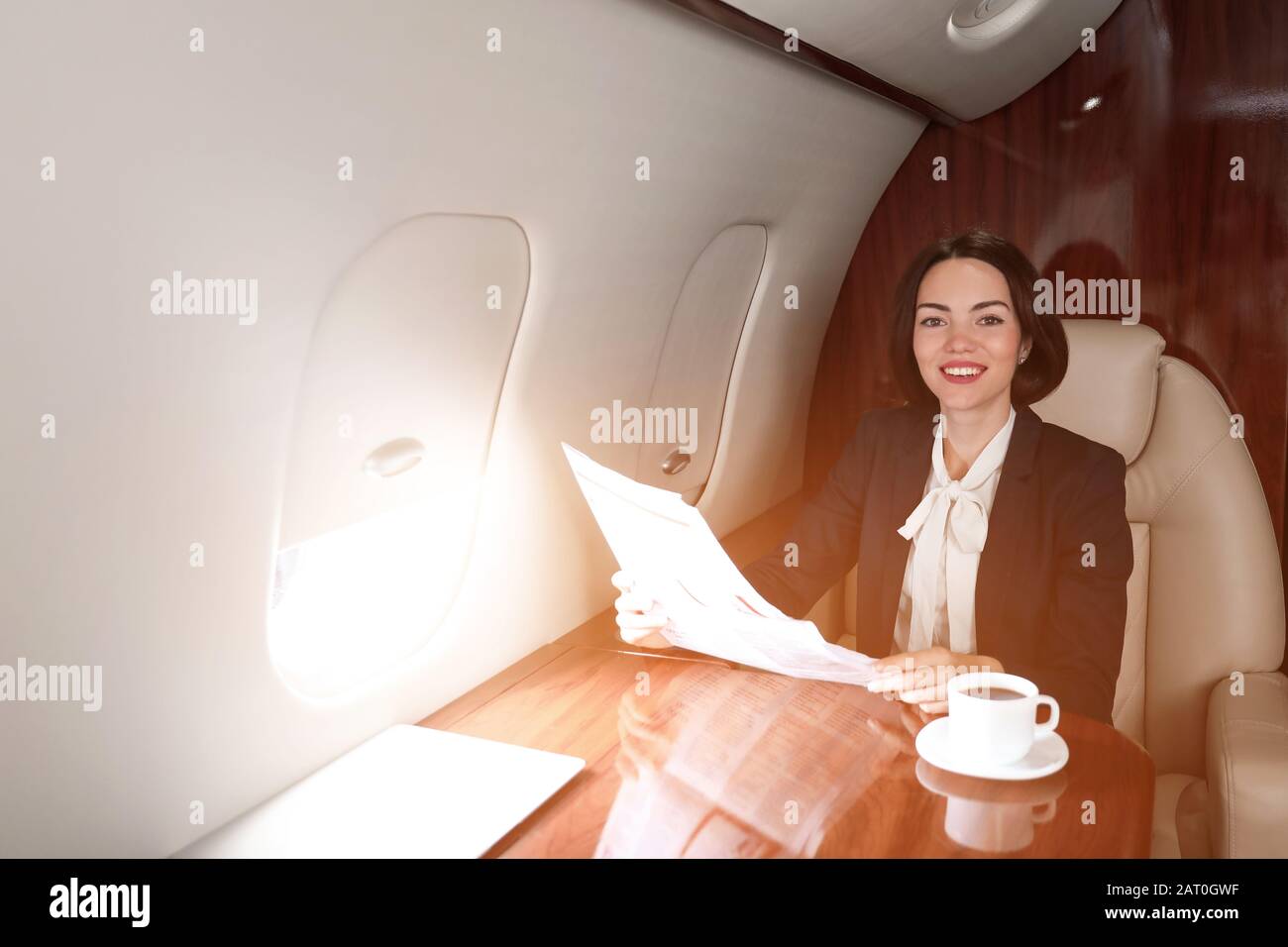 Businesswoman reading newspaper on board the modern private airplane ...