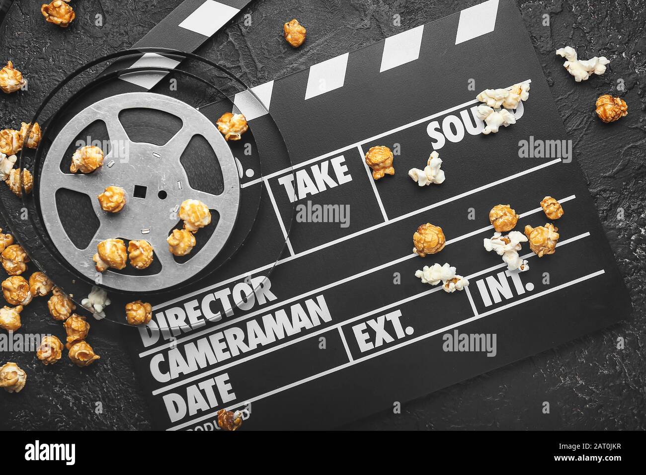 Tasty popcorn with movie clapper and film on dark background Stock ...