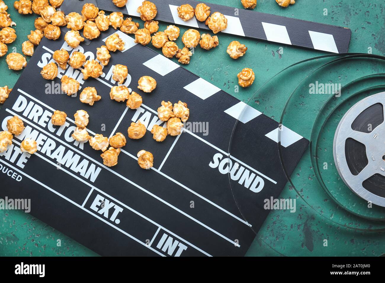 Tasty popcorn with movie clapper and film on color background Stock ...