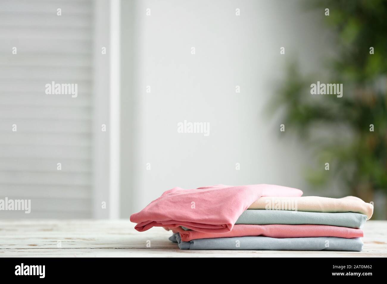 Stack of clean clothes on table in room Stock Photo - Alamy