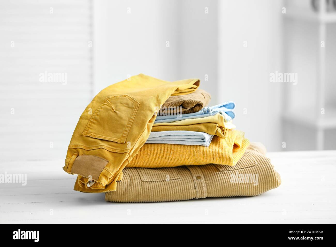 Stack of clean clothes on table in room Stock Photo - Alamy