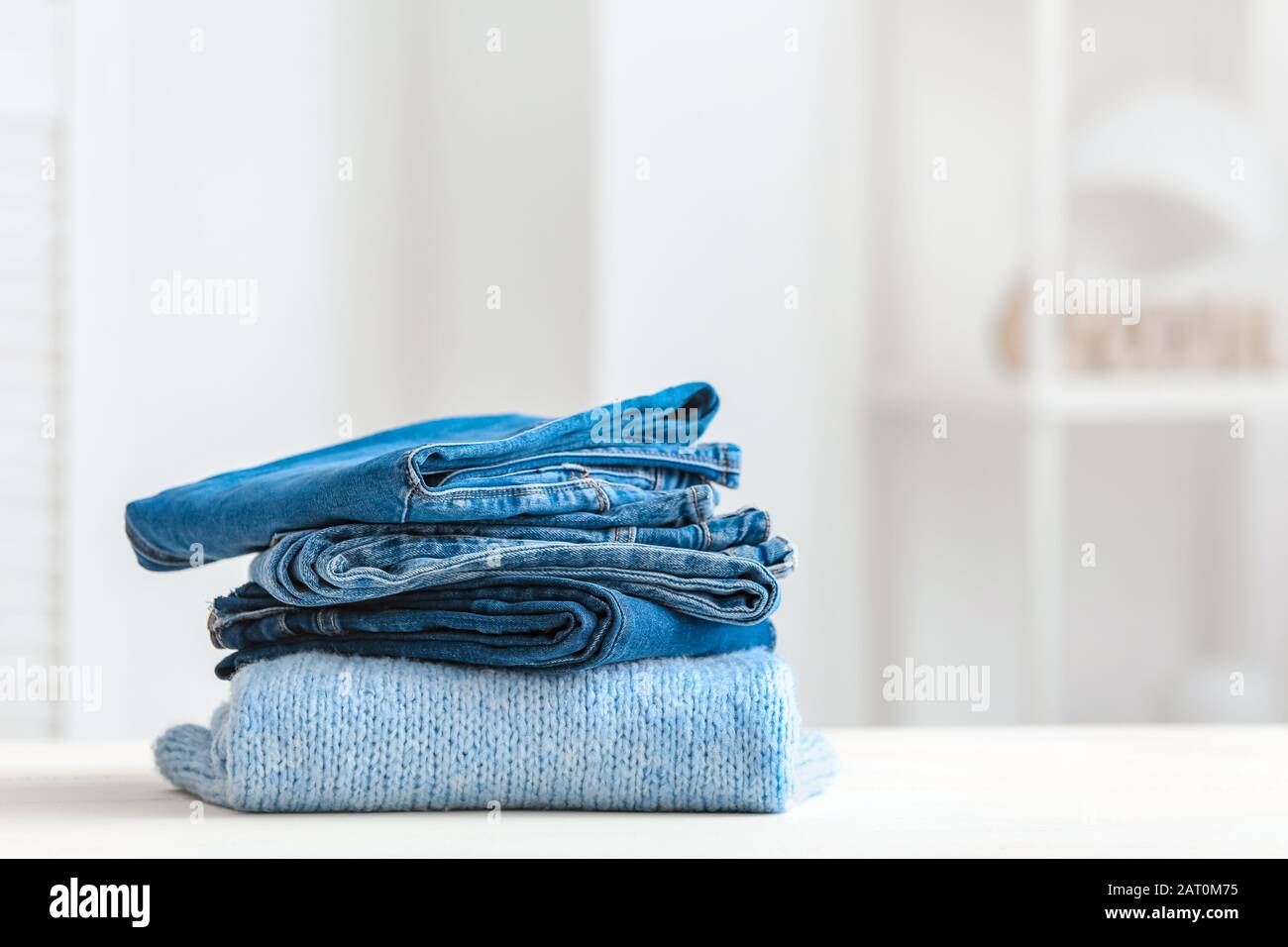 Stack of clean clothes on table in room Stock Photo - Alamy