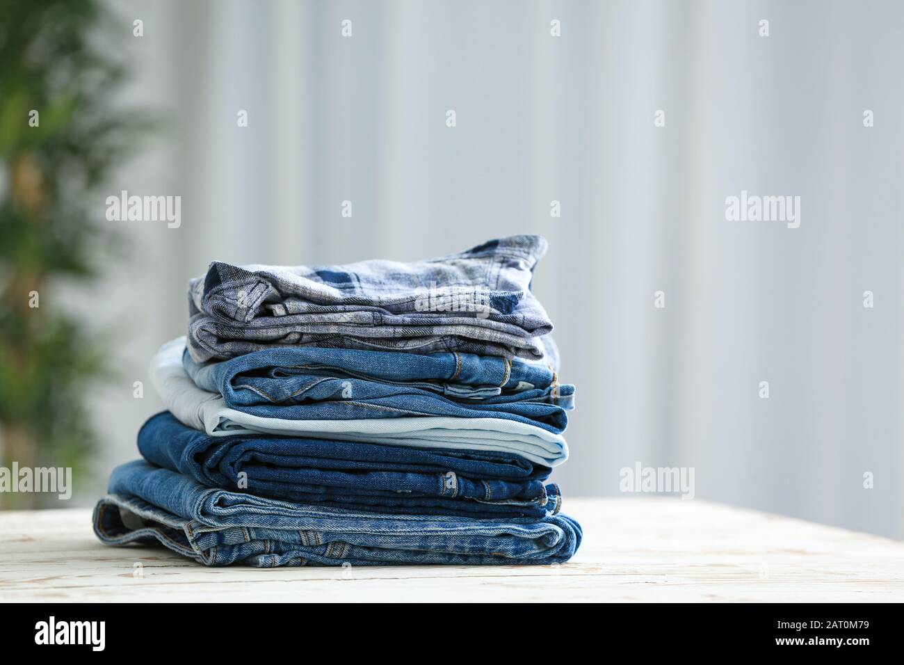 Stack of clean clothes on table in room Stock Photo - Alamy
