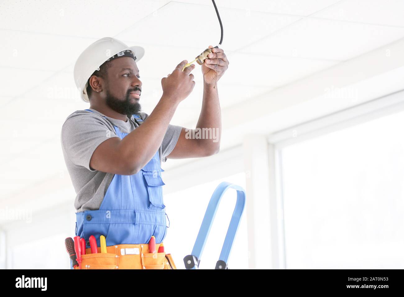 African-American electrician performing wiring in room Stock Photo - Alamy