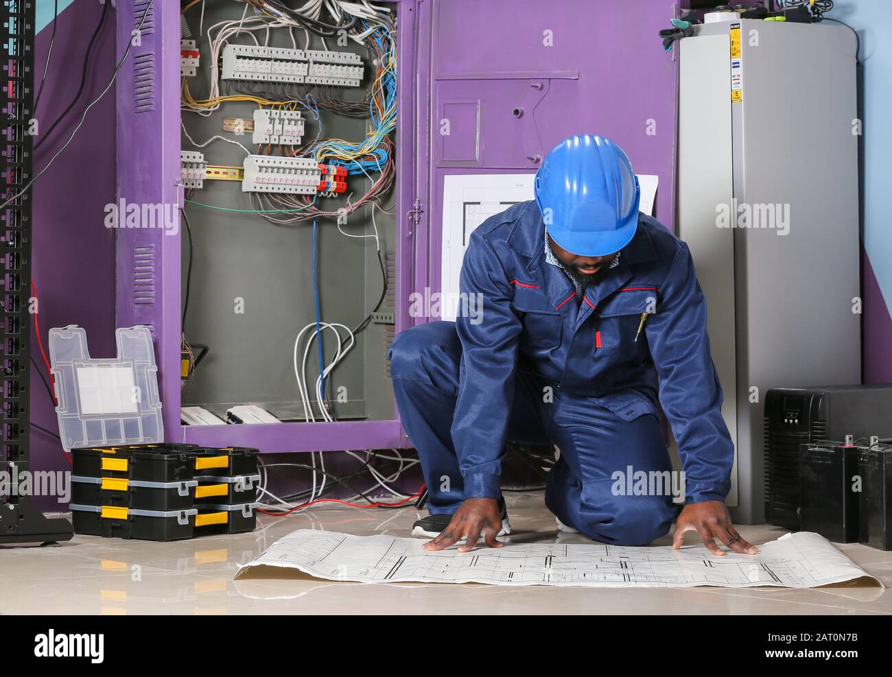 African-American electrician with plan of house indoors Stock Photo - Alamy