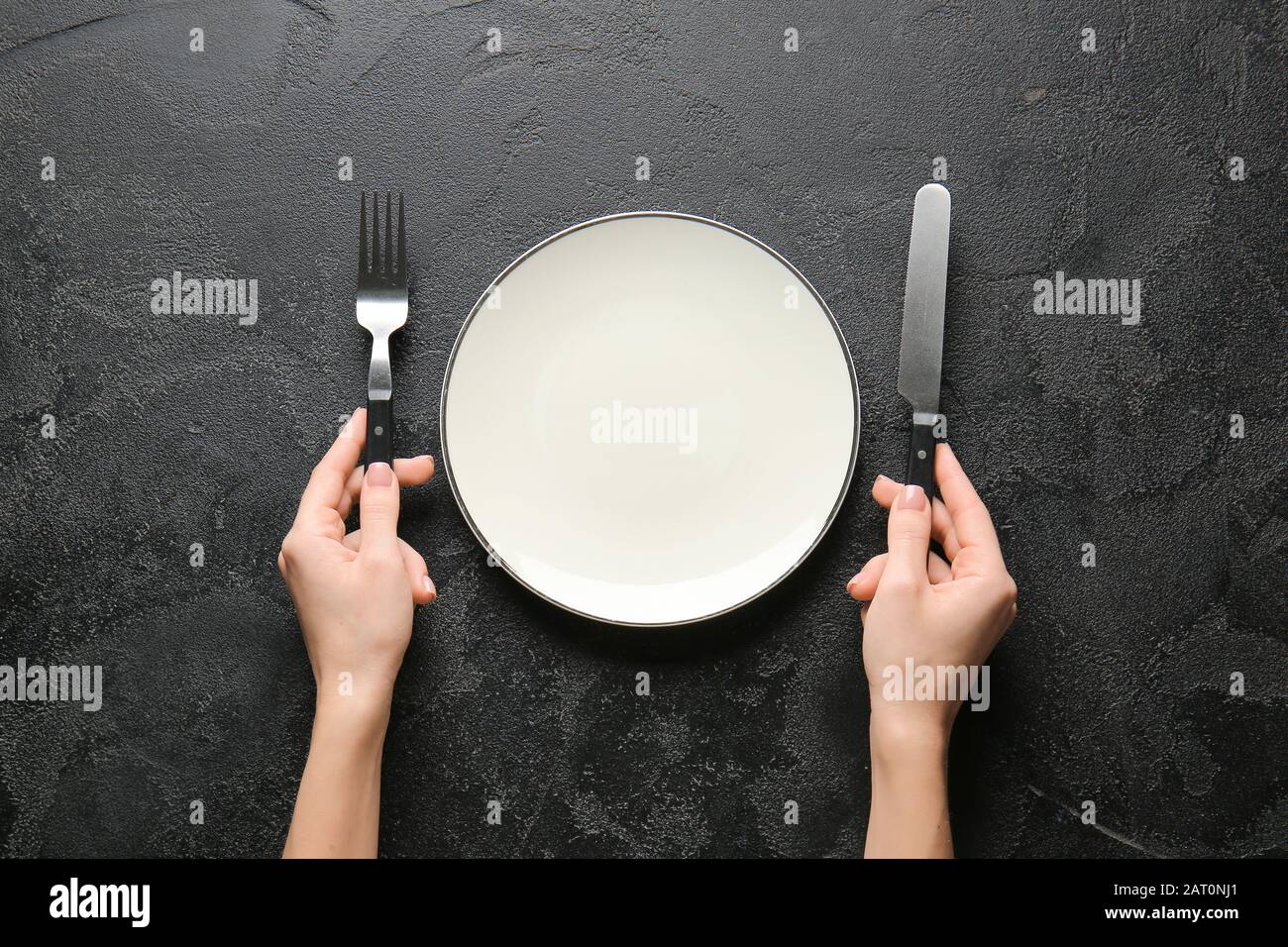 Woman with empty plate and cutlery at table Stock Photo - Alamy