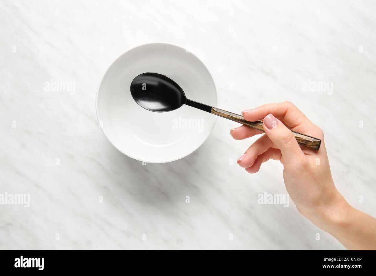 Female hand with spoon and empty bowl on light background Stock Photo ...