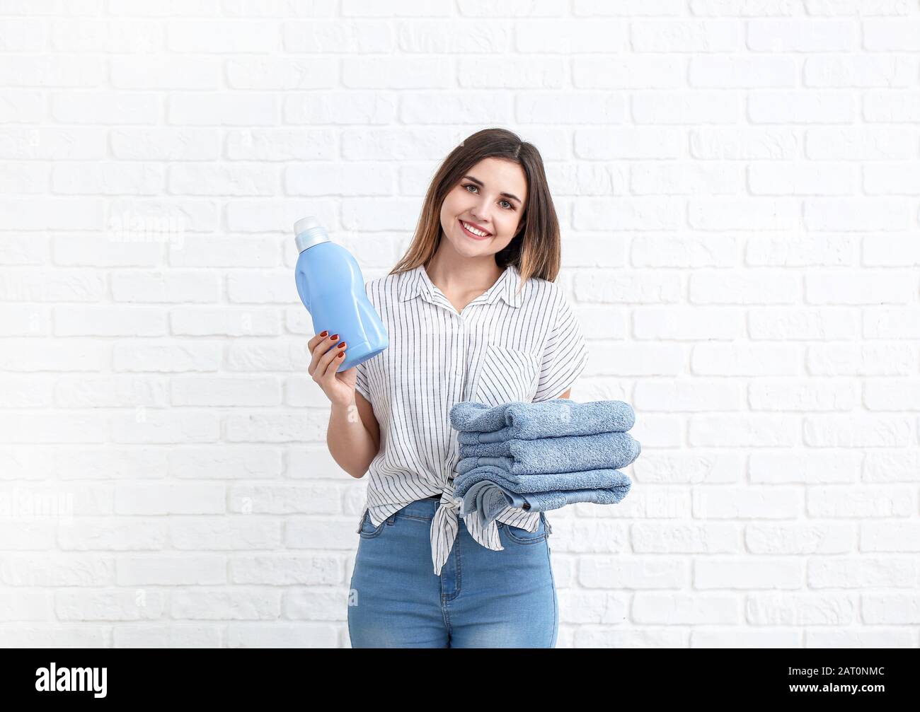 Beautiful young woman with laundry on white brick background Stock ...
