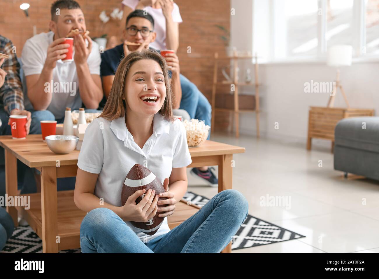 Young woman with friends watching rugby on TV Stock Photo - Alamy