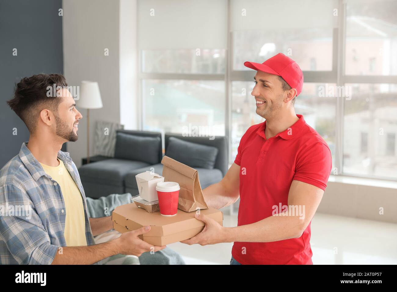 Man receiving order from courier of food delivery company Stock Photo ...