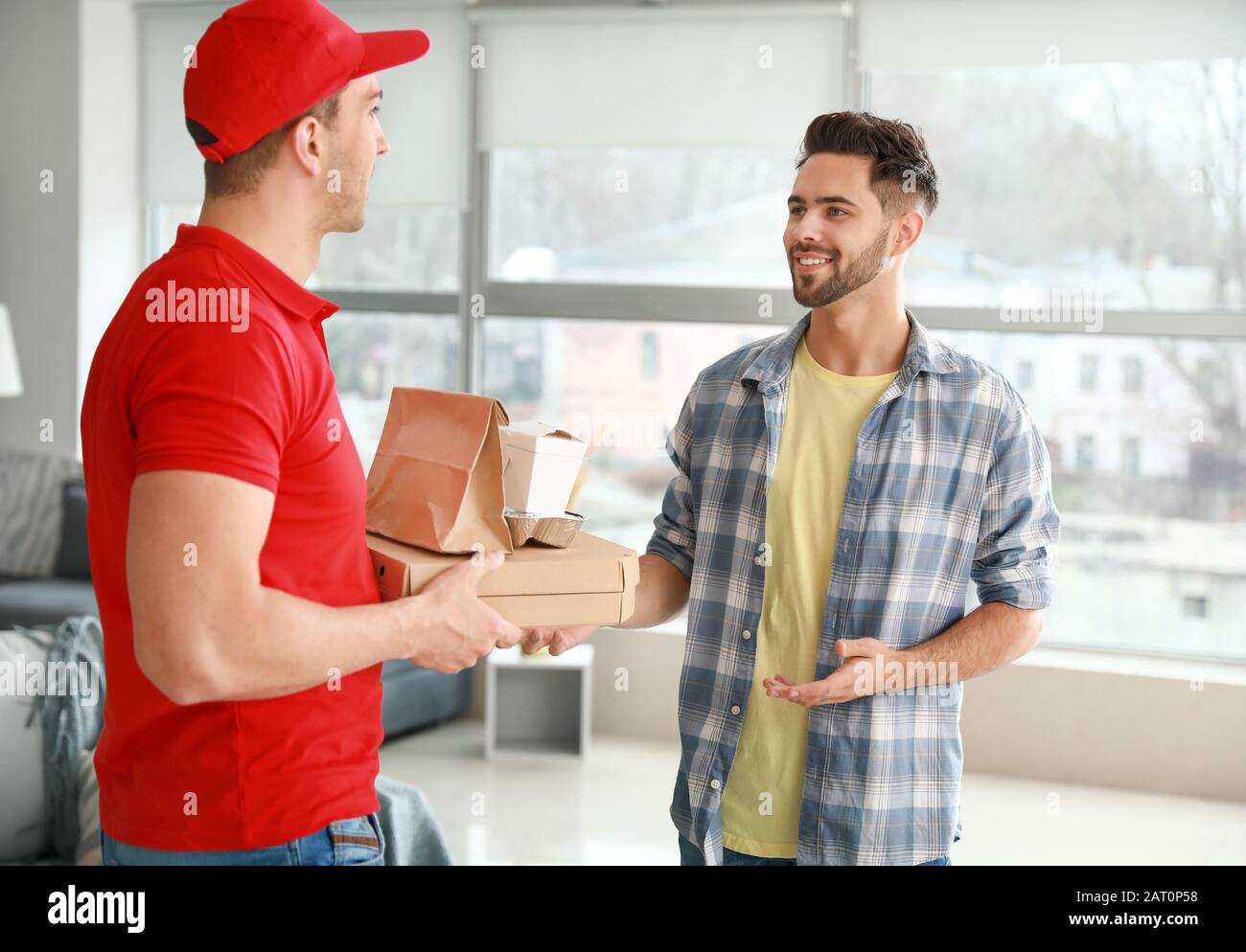 Man receiving order from courier of food delivery company Stock Photo ...
