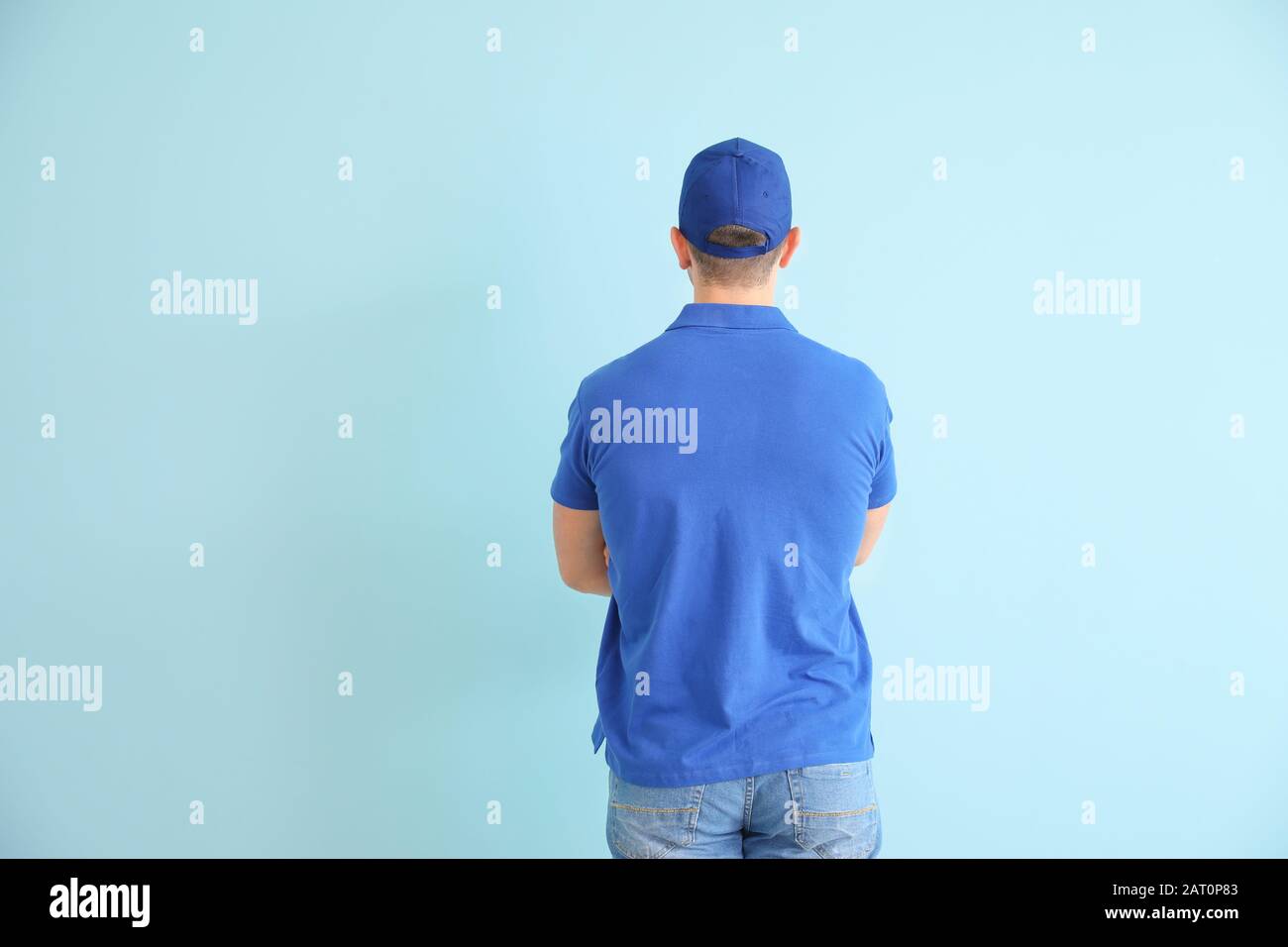 Handsome delivery man on color background, back view Stock Photo - Alamy