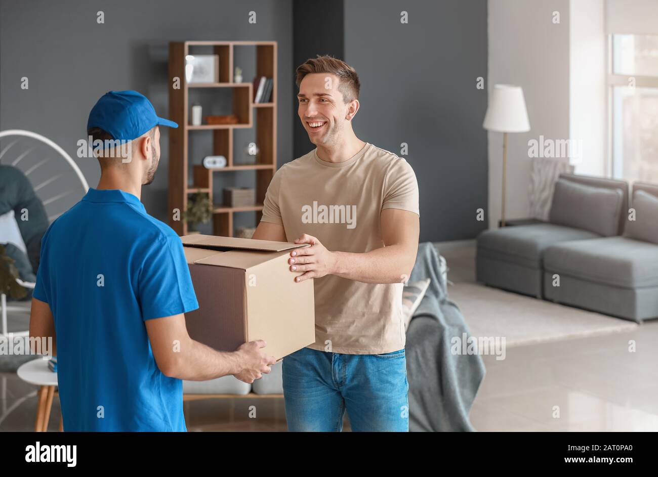 Man receiving parcel from courier of delivery service at home Stock ...