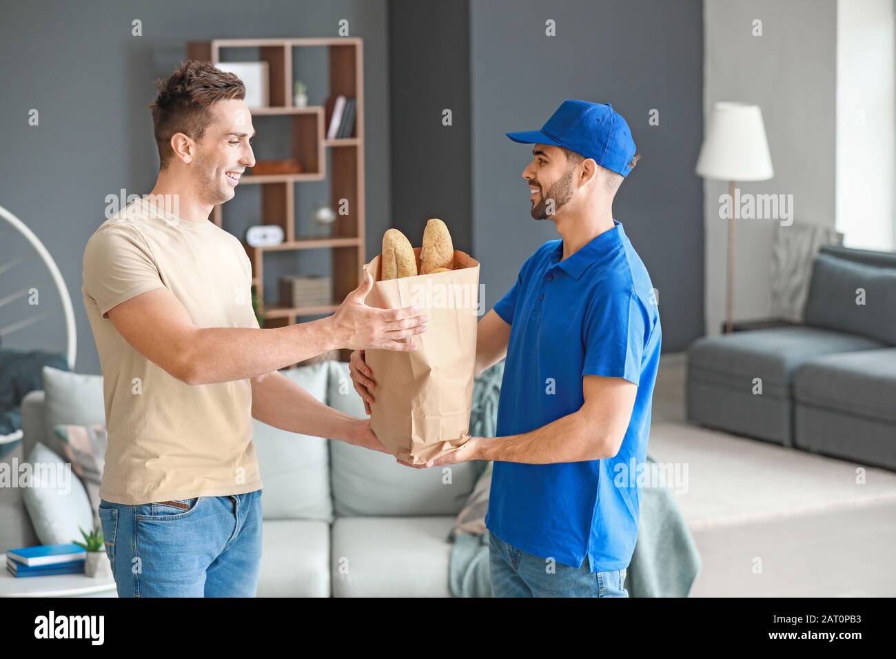 Man receiving order from courier of food delivery company Stock Photo ...