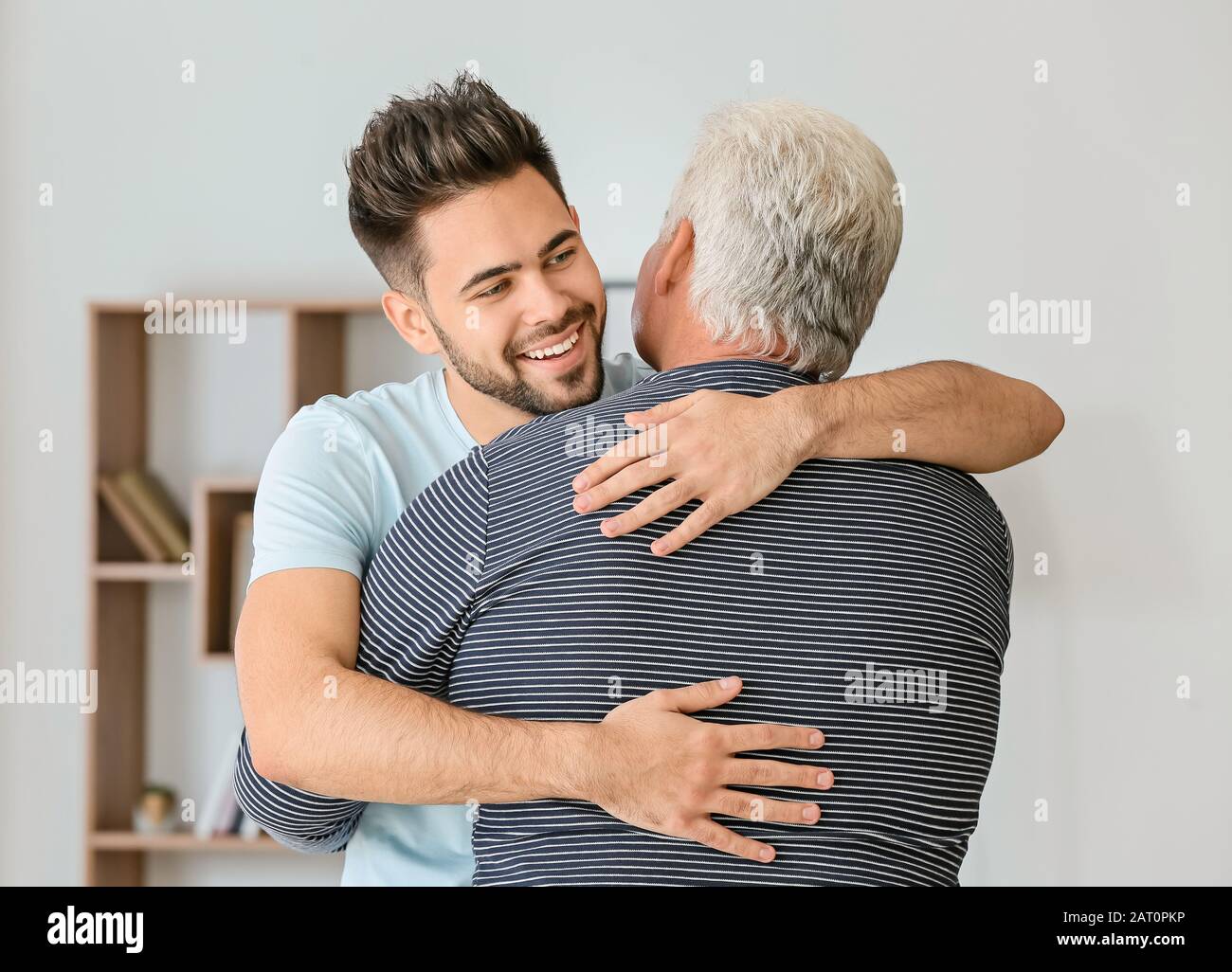 Young man and his father hugging at home Stock Photo - Alamy