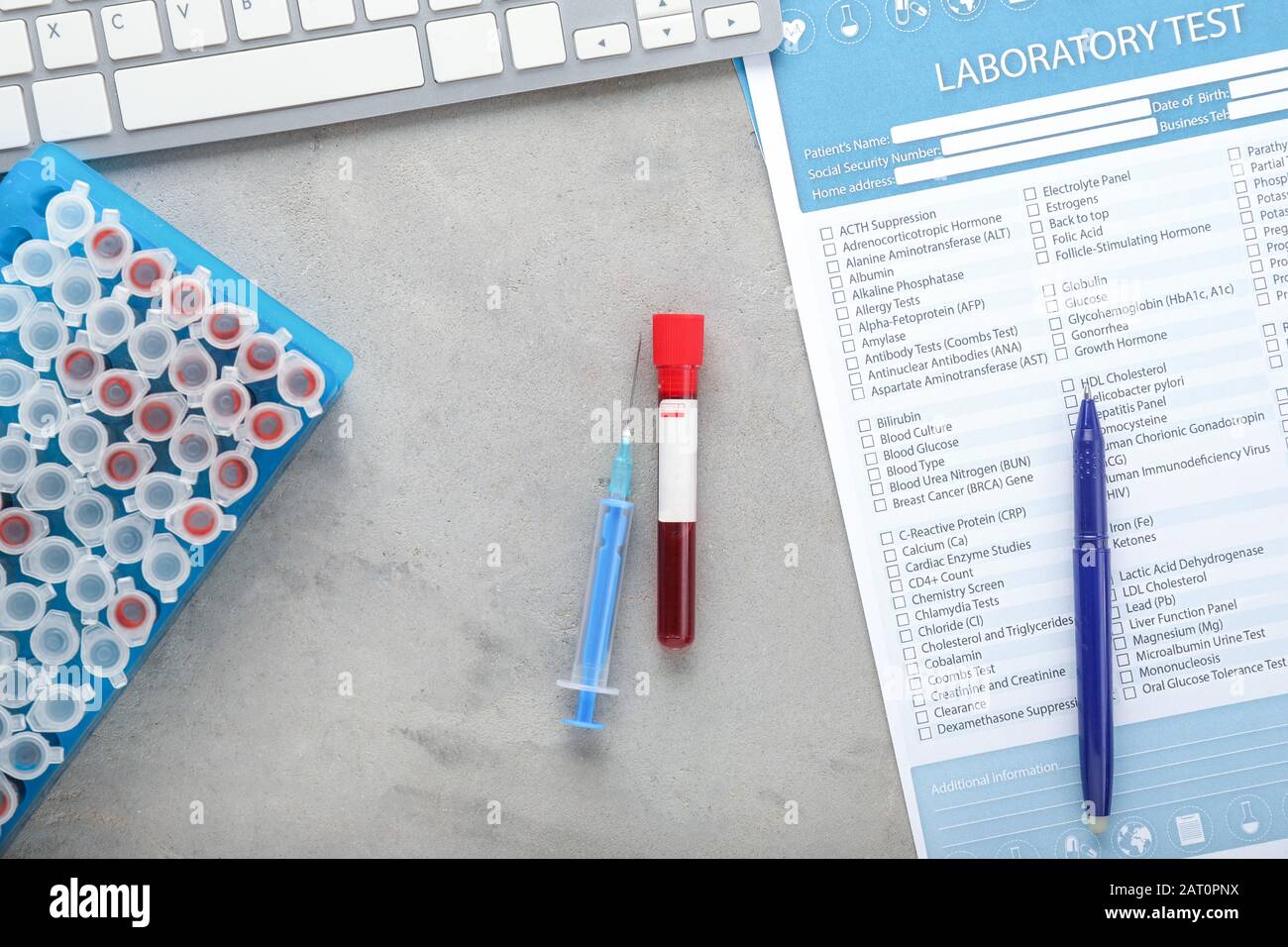 Laboratory test form, PC keyboard, syringe and blood samples on table ...