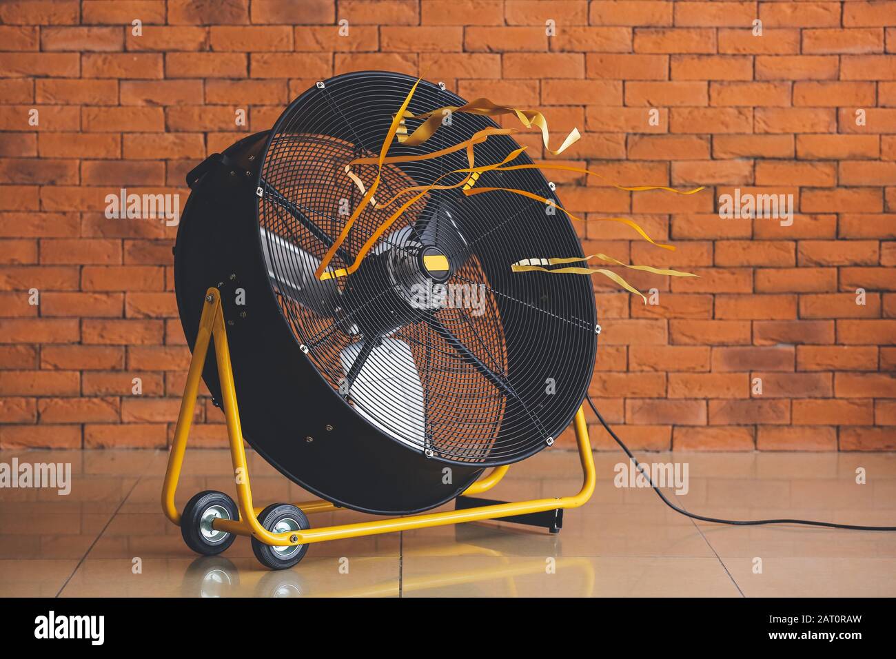 Electric fan with fluttering ribbons near brick wall Stock Photo - Alamy