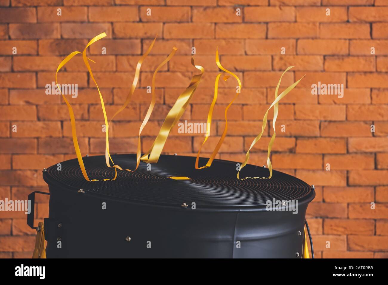 Electric fan with fluttering ribbons near brick wall Stock Photo - Alamy