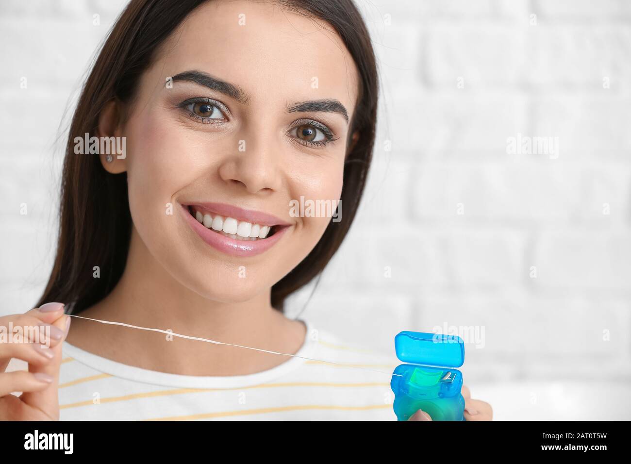 Beautiful young woman with dental floss on light background Stock Photo ...