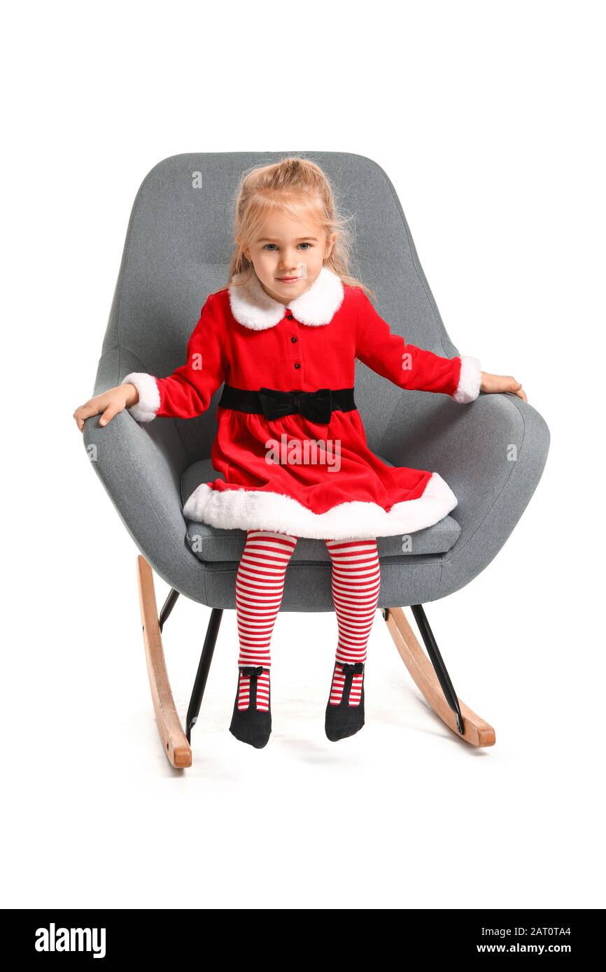 Cute little girl in Santa costume sitting on chair against white ...