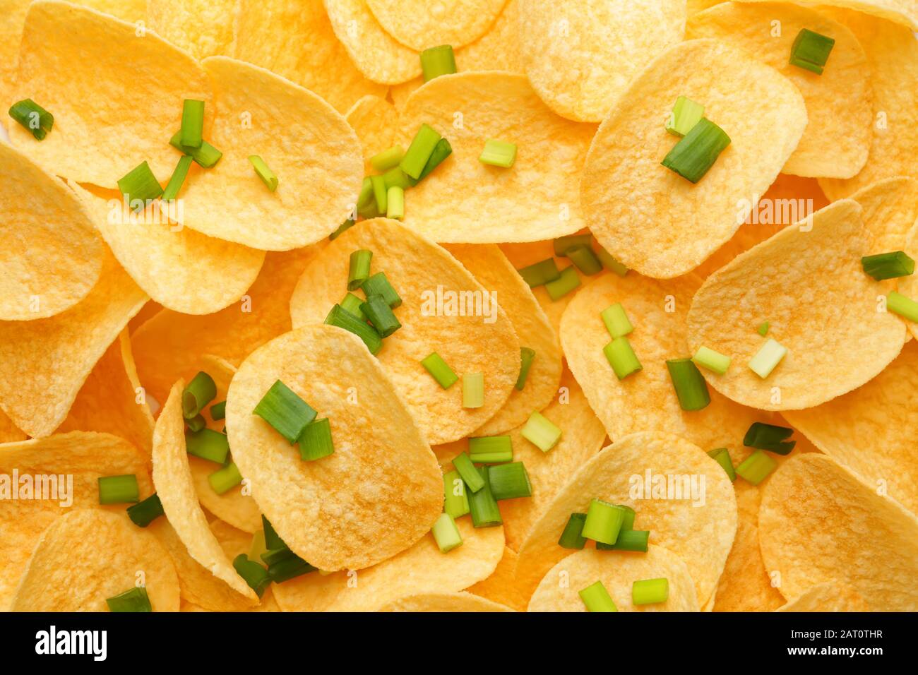 Tasty potato chips with green onion as background Stock Photo - Alamy