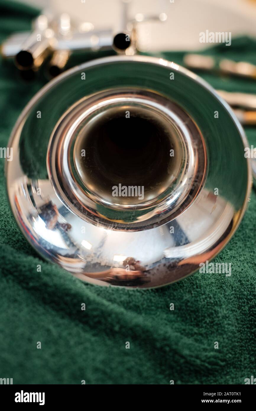 Shiny reflective bell of a disassembled silver trumpet lying on a green ...