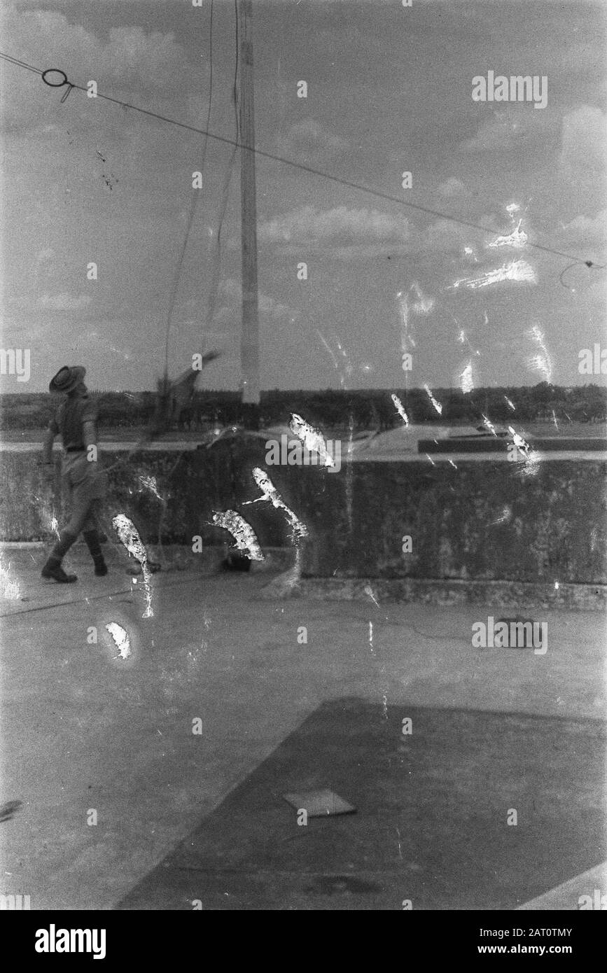 A KNIL (or Republican?) military takes a flag down, atop a building ...