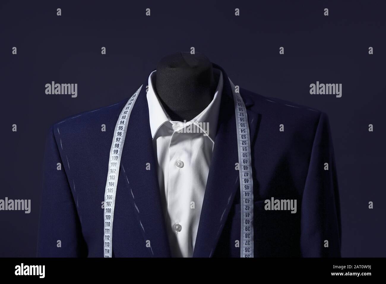 Tailor's mannequin with unfinished clothes and measuring tape on dark ...
