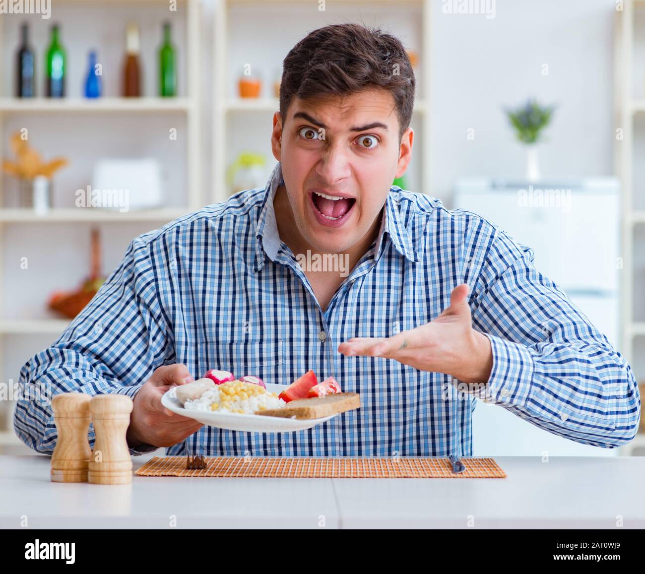 The young husband eating tasteless food at home for lunch Stock Photo ...