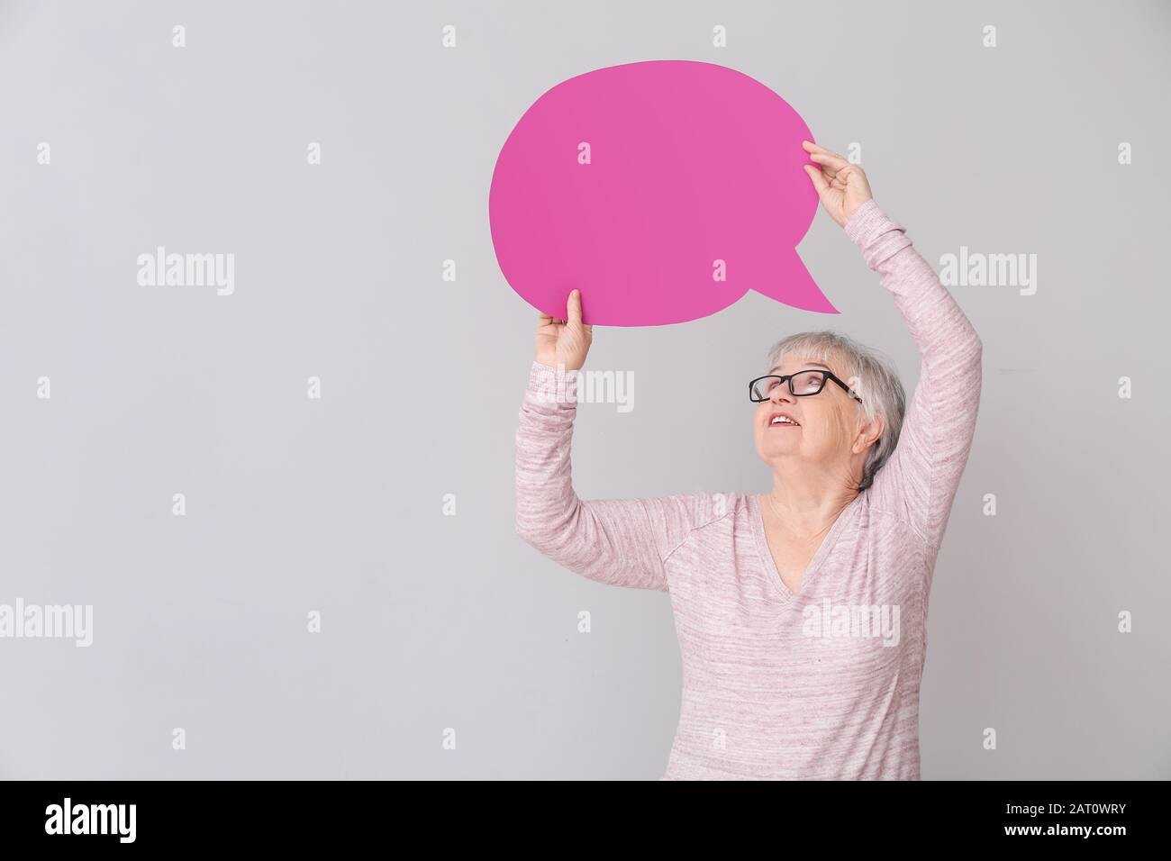 Senior woman with blank speech bubble on grey background Stock Photo ...