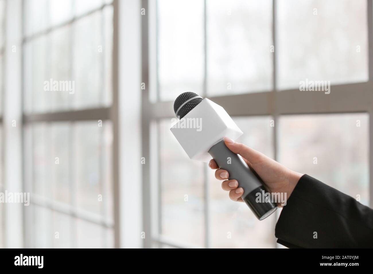 Female journalist with microphone indoors Stock Photo - Alamy