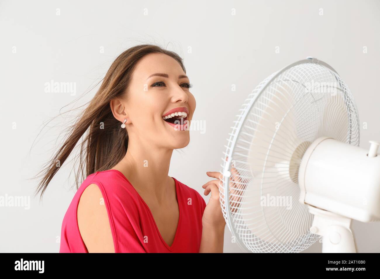 Happy woman with electric fan on white background Stock Photo - Alamy