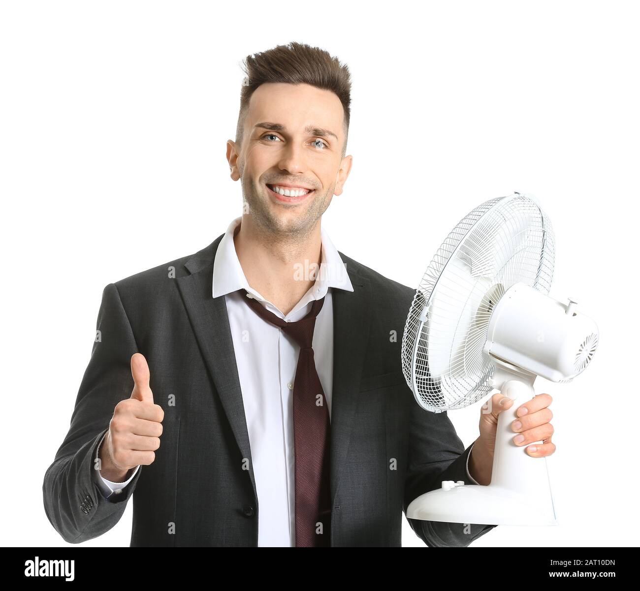 Young man with electric fan showing thumb-up gesture on white ...