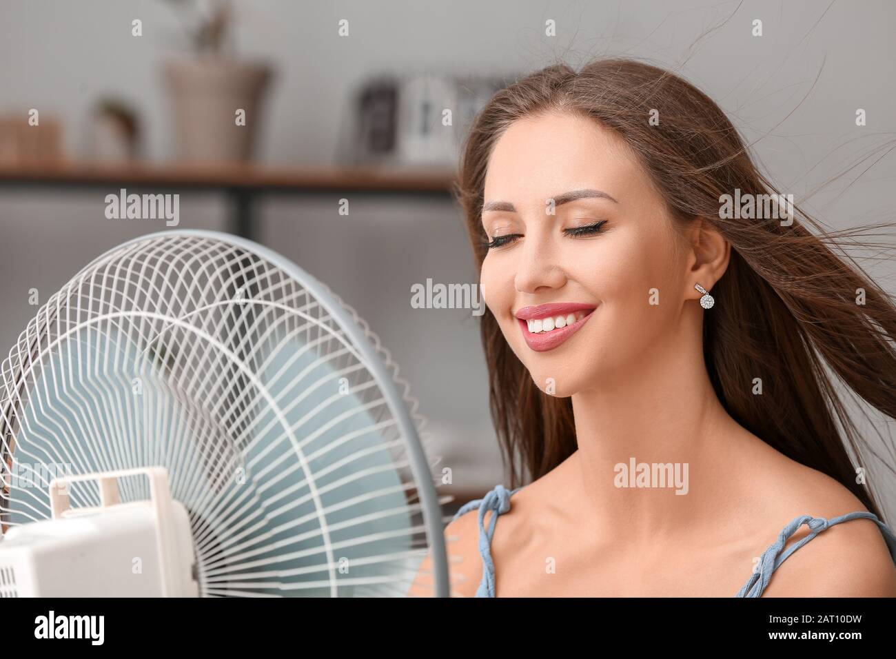 Young woman using electric fan during heatwave at home Stock Photo - Alamy