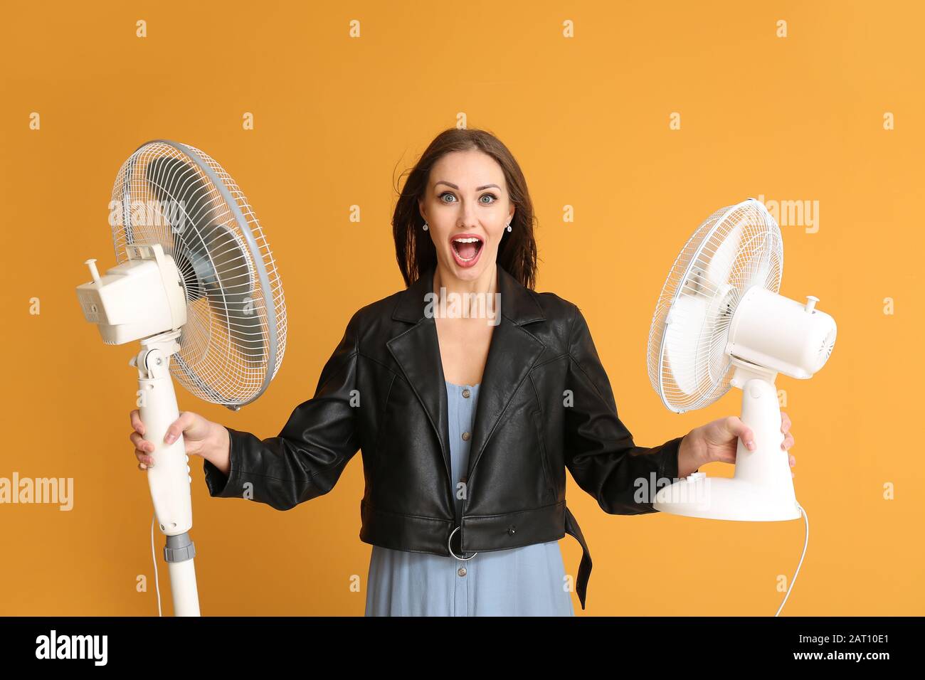 Surprised woman with electric fans on color background Stock Photo - Alamy