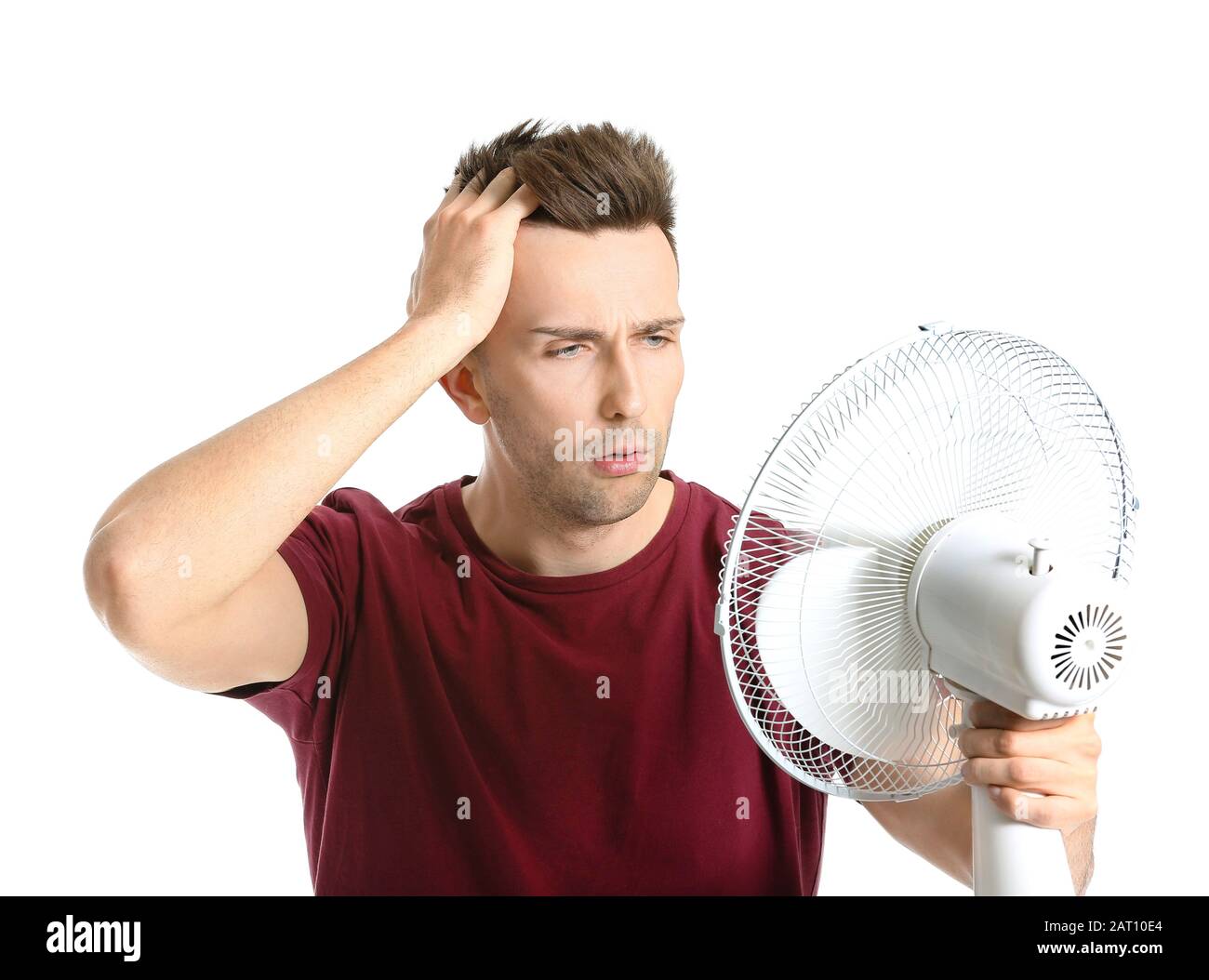 Confused man with electric fan on white background Stock Photo - Alamy