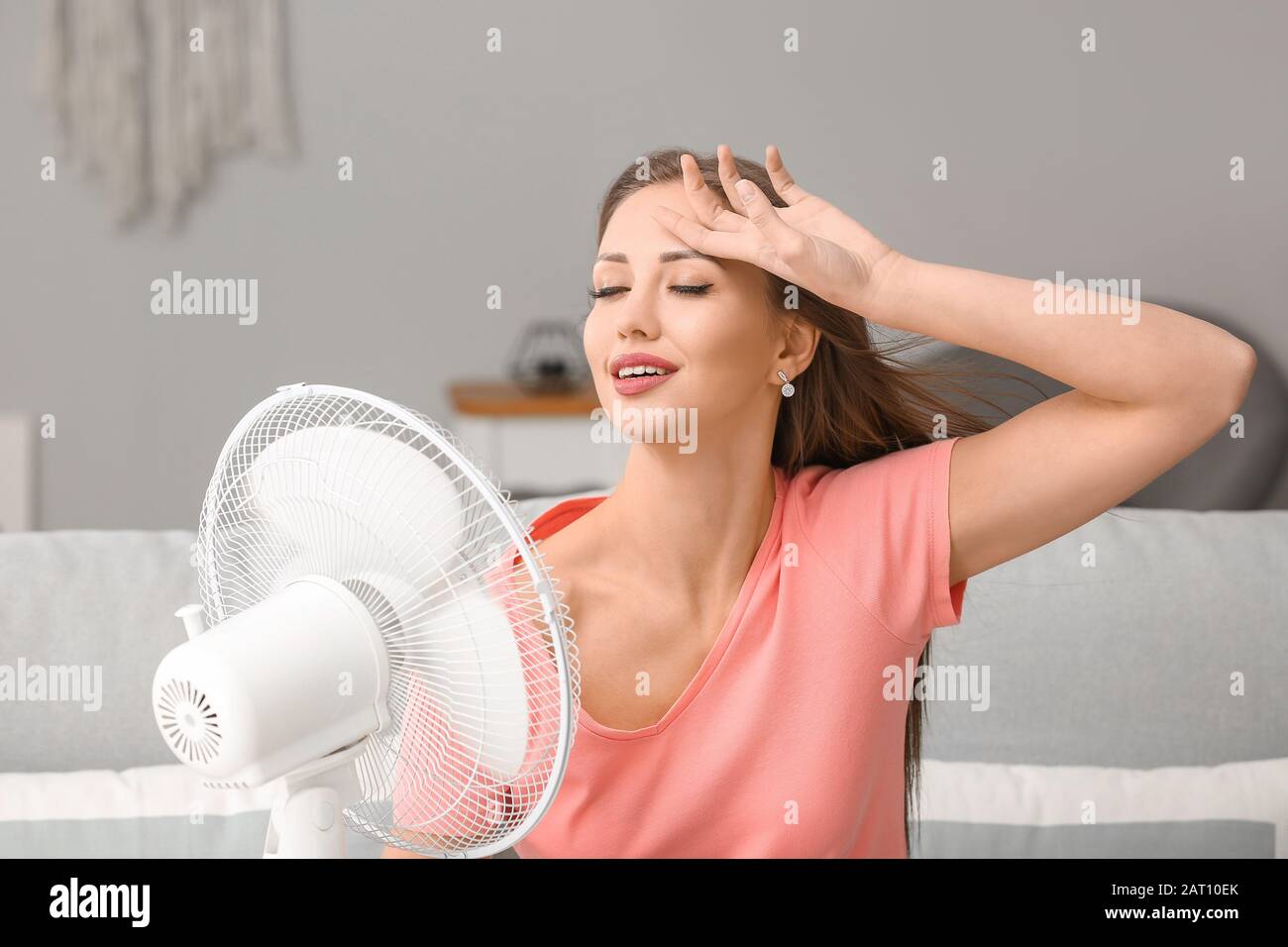 Young woman using electric fan during heatwave at home Stock Photo - Alamy