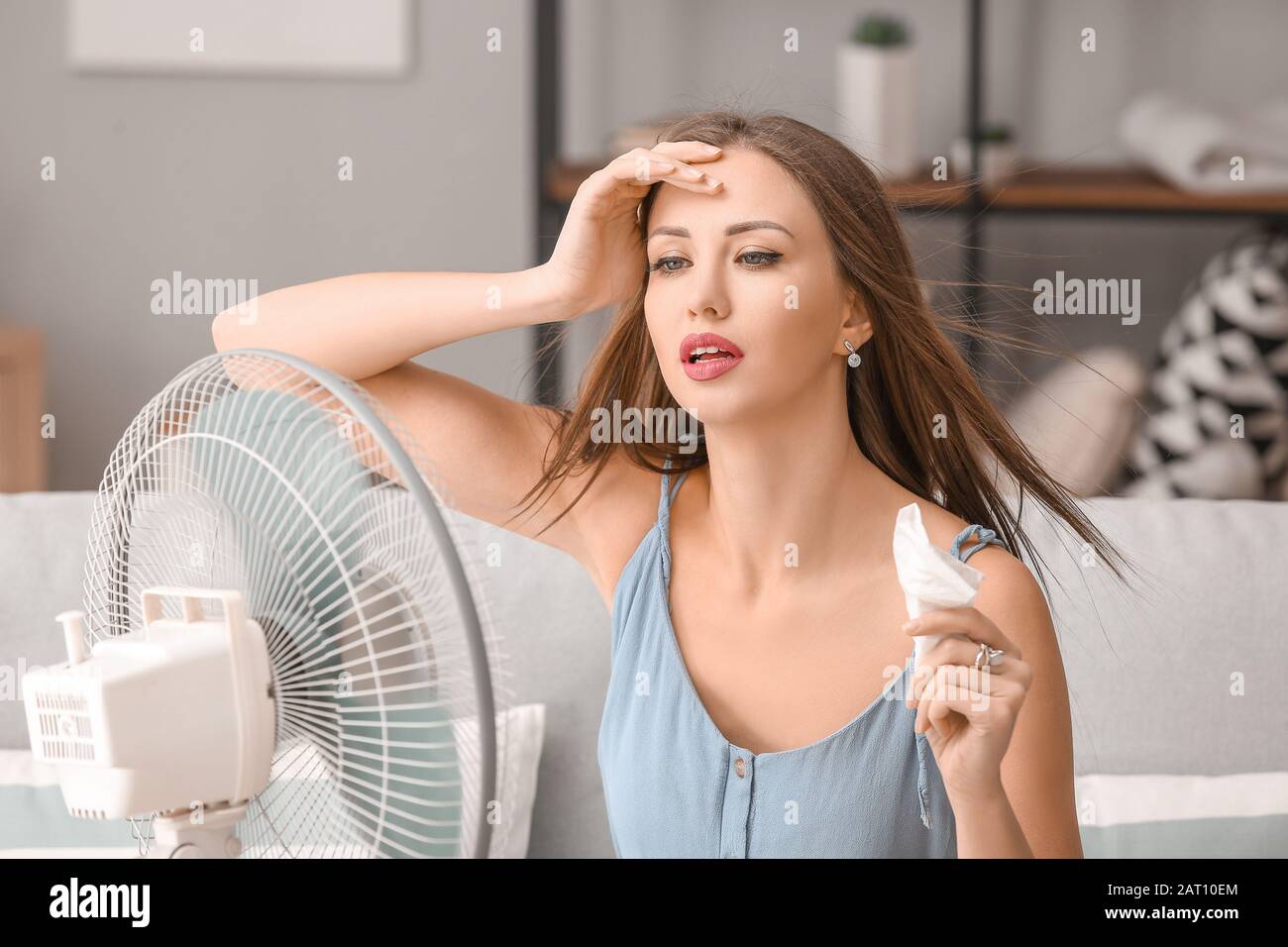 Young woman using electric fan during heatwave at home Stock Photo - Alamy