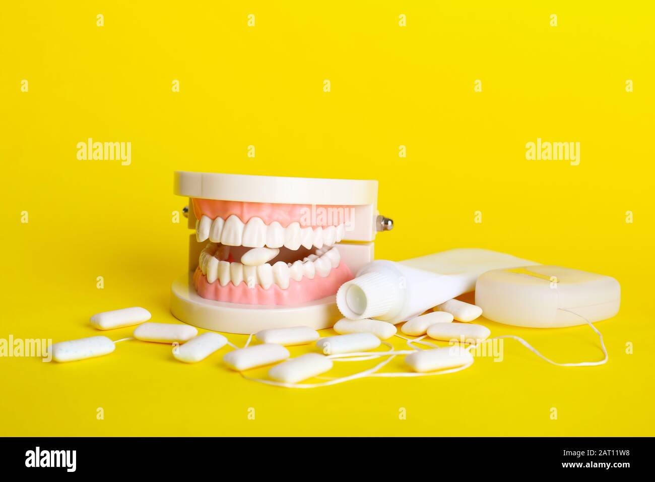 Plastic jaw, tooth paste, floss and chewing gums on color background ...