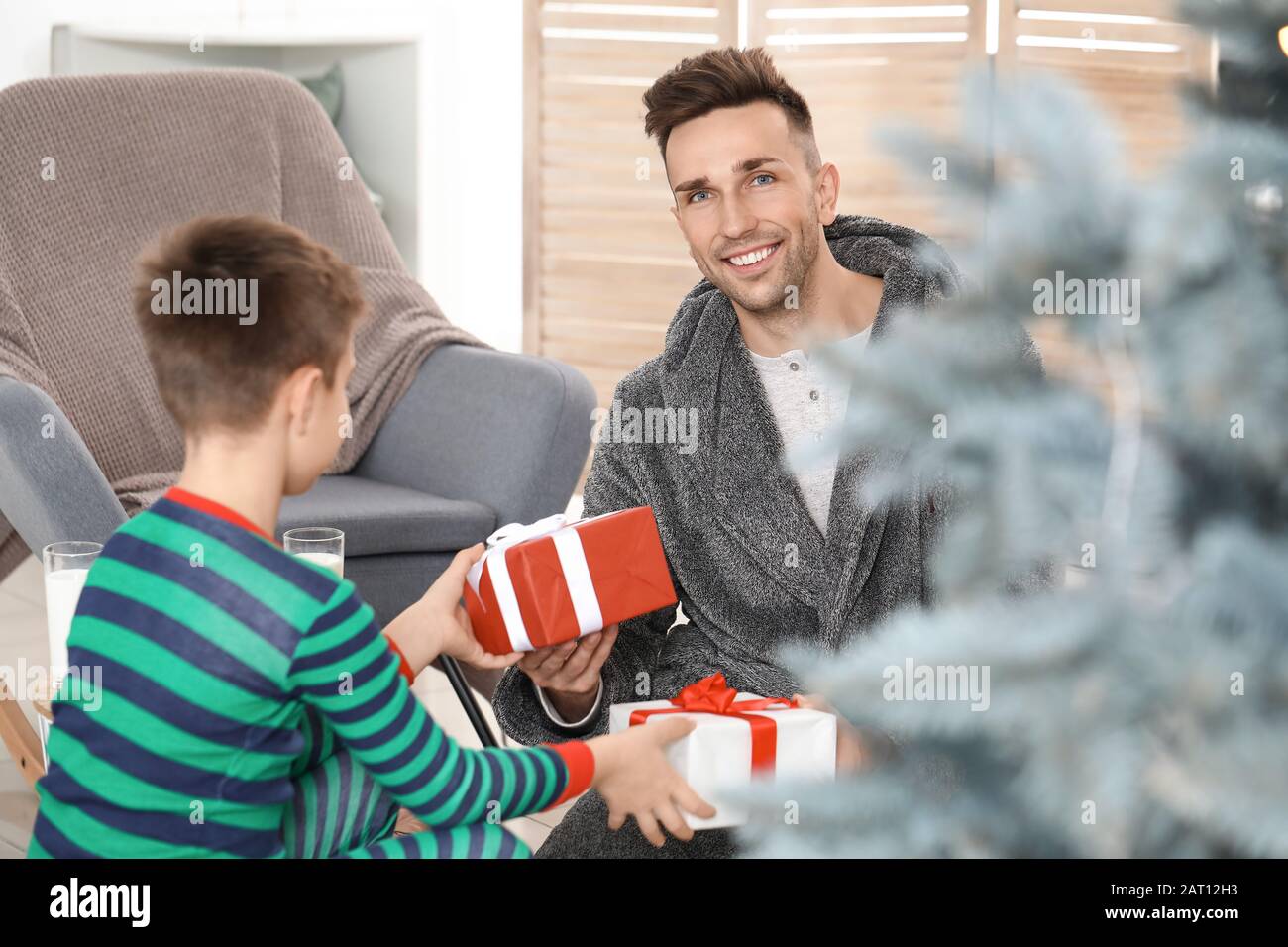 Father and his little son giving each other Christmas presents at home ...