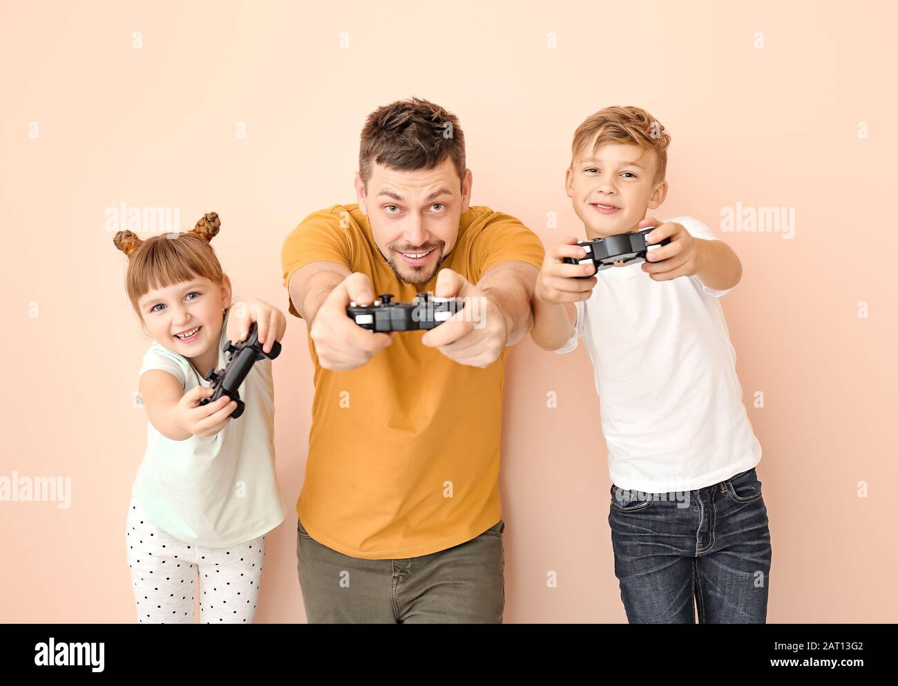 Father and his little children playing video games on color background ...